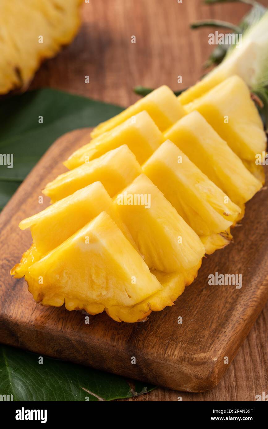 Close up of fresh cut pineapple on a tray over dark wooden table ...