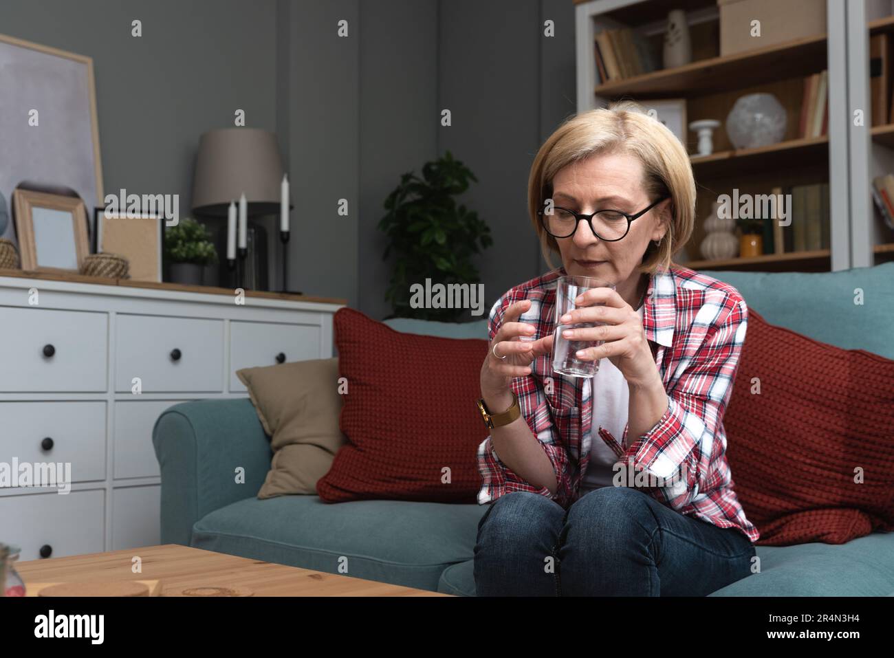 Pensive thoughtful middle aged lady looking away sit alone at home feel ...