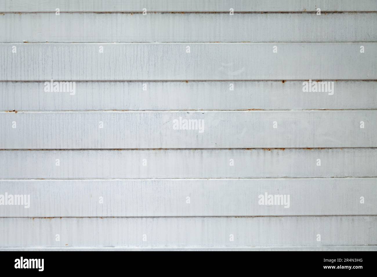 Gray painted surface of a corrugated metal gate with ridges and grooves ...