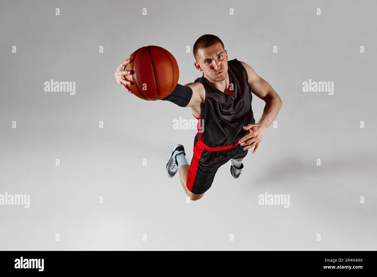 Concentrated sportsman, male basketball player in motion, jumping with ...