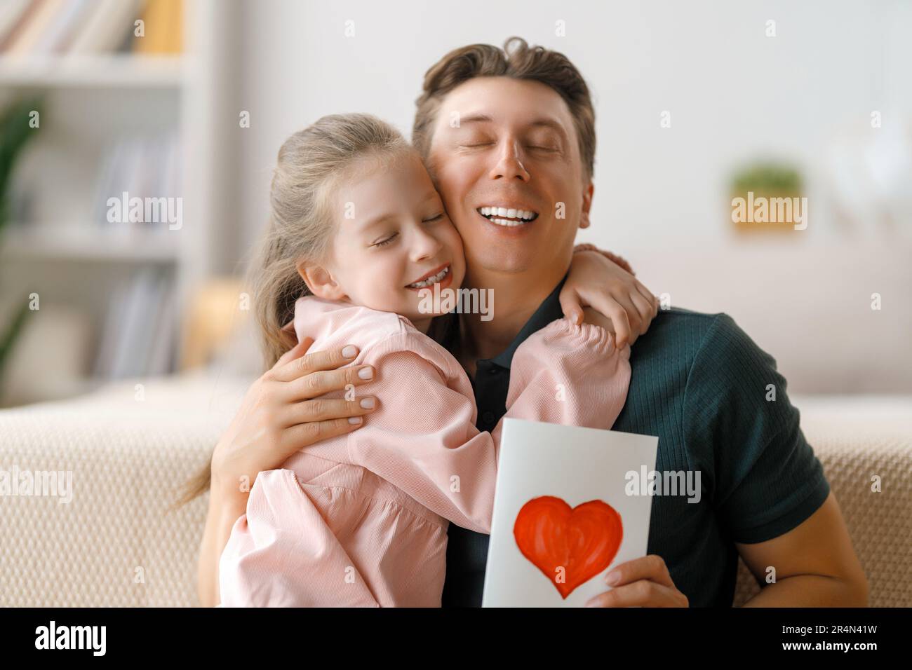 Child daughter is congratulating her father and giving him postcard ...
