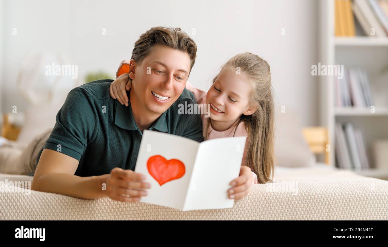 Child daughter is congratulating her father and giving him postcard ...