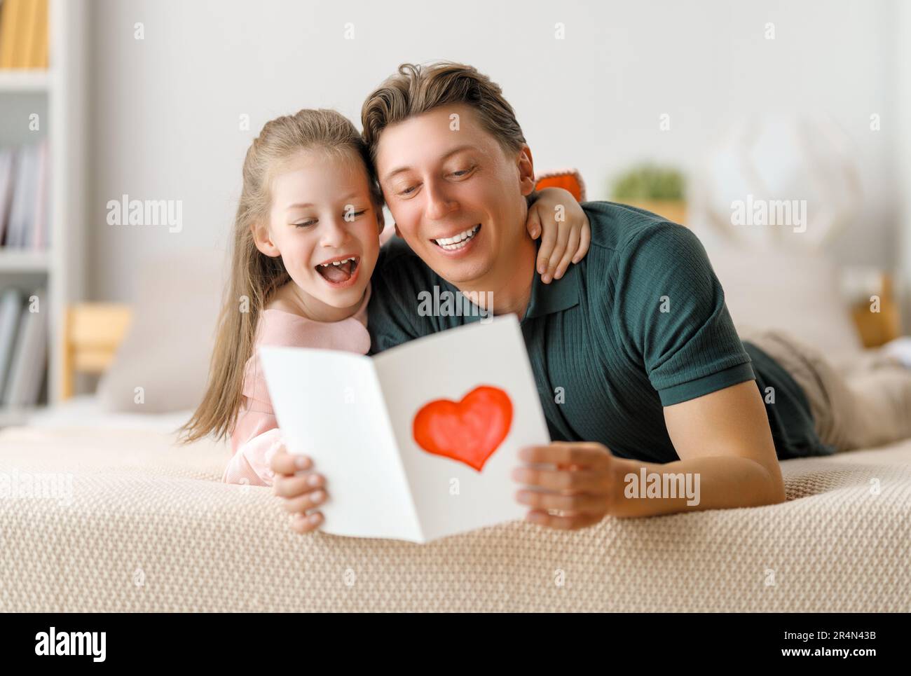 Child daughter is congratulating her father and giving him postcard ...