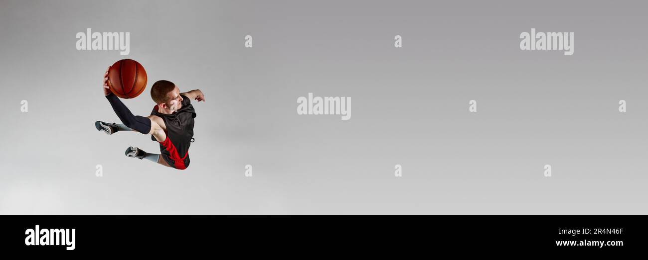 Slam dunk. Young man, basketball player in motion, jumping with ball ...