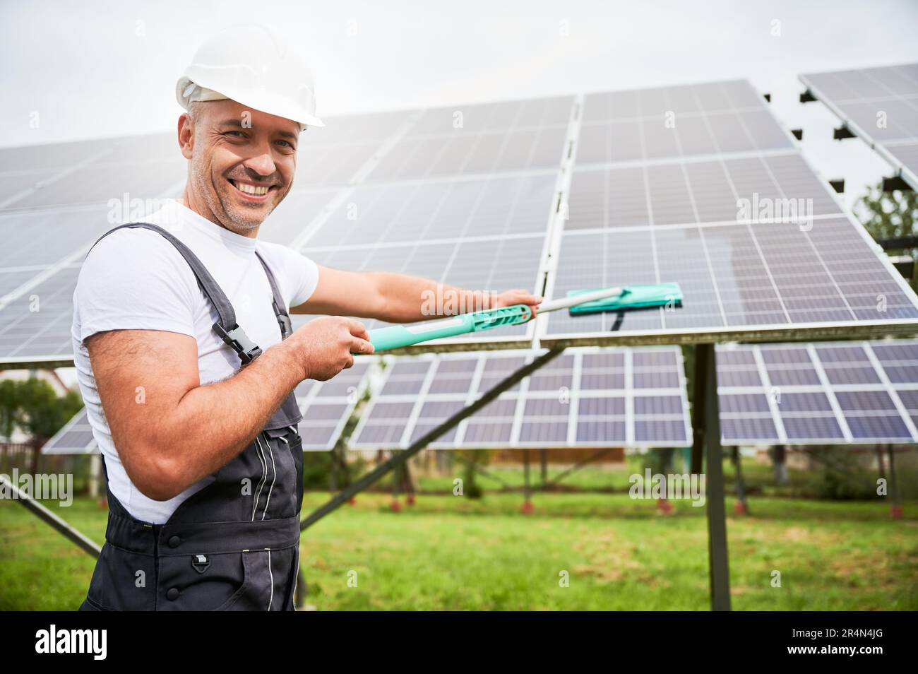 Professional worker cleaning solar panel from dust. Smiling man wiping ...