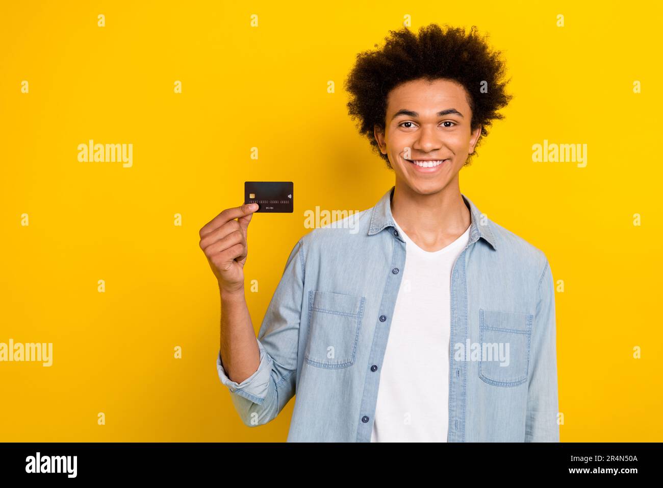 Photo of cheerful cute guy dressed denim shirt rising bank card empty ...