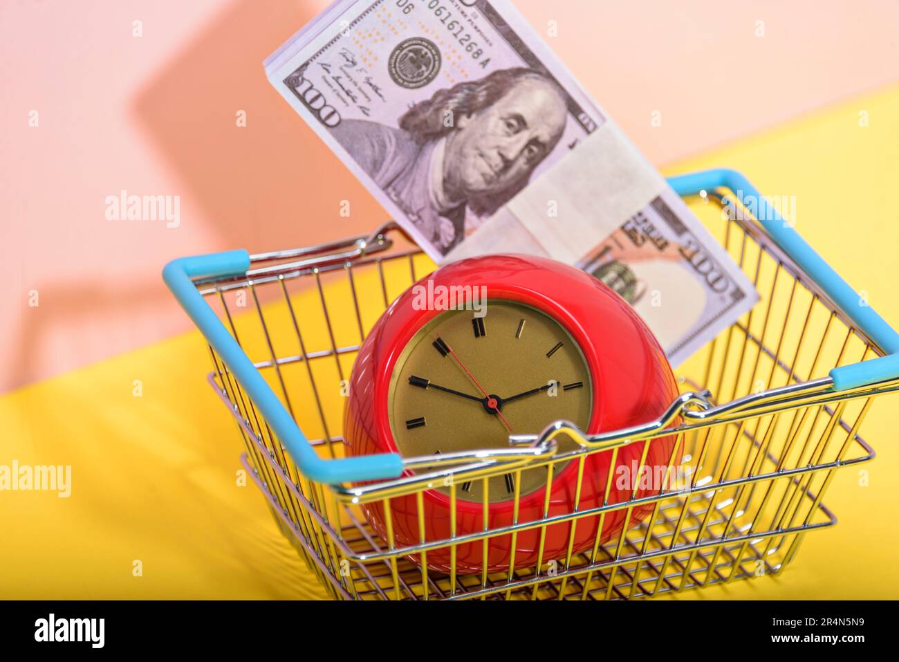 A supermarket trolley with old vintage alarm clock on pink and yellow ...