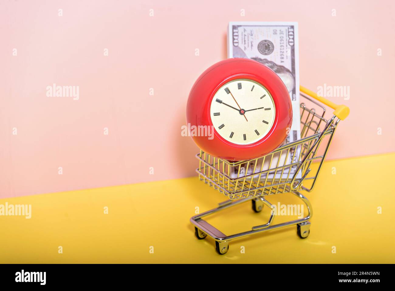A supermarket trolley with old vintage alarm clock on pink and yellow ...