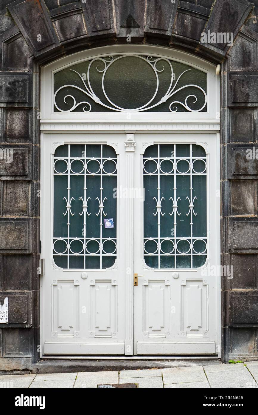 Ornate, white, double doors set into black lava stone building ...