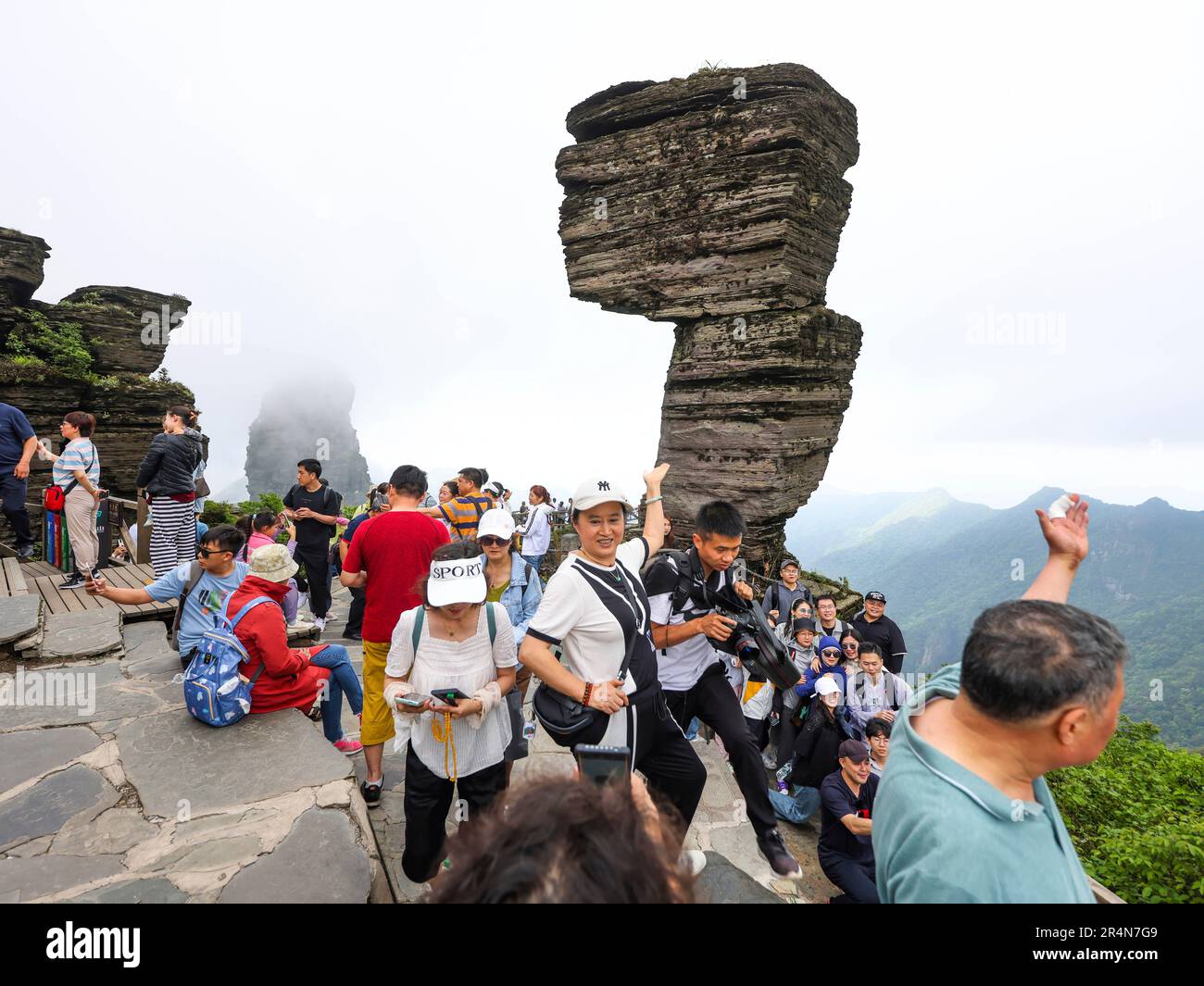 Tourists admire the scenery on top of a rock of Fanjingshan Mountain in ...