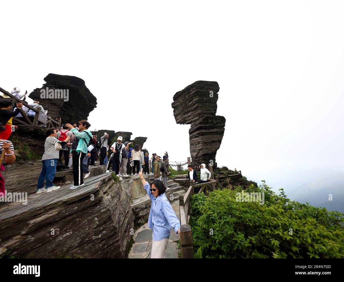 Tourists admire the scenery on top of a rock of Fanjingshan Mountain in ...