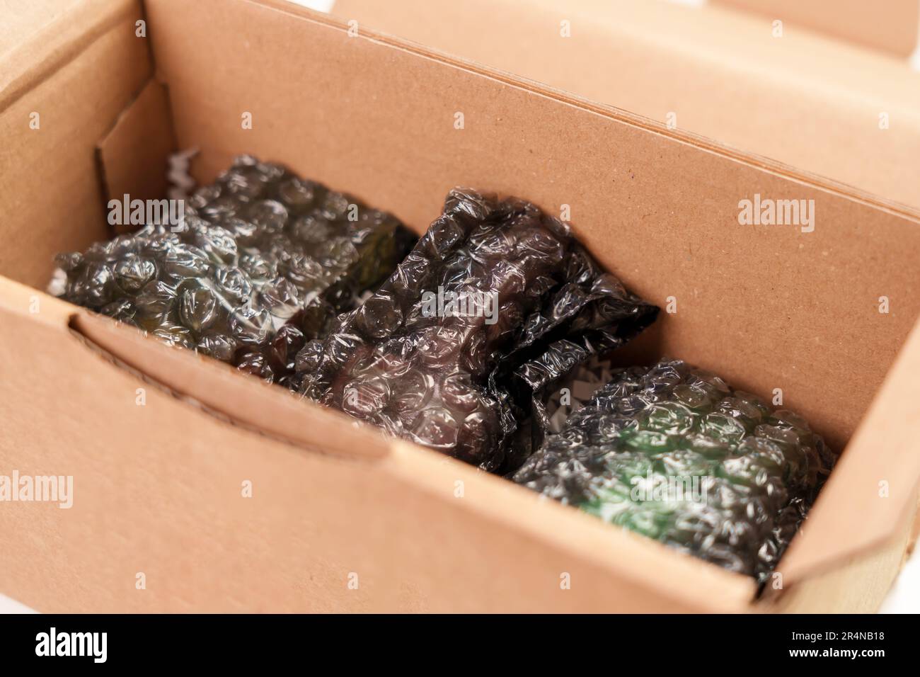 Opened cardboard gift parcel box with bubble wrapped items close up ...