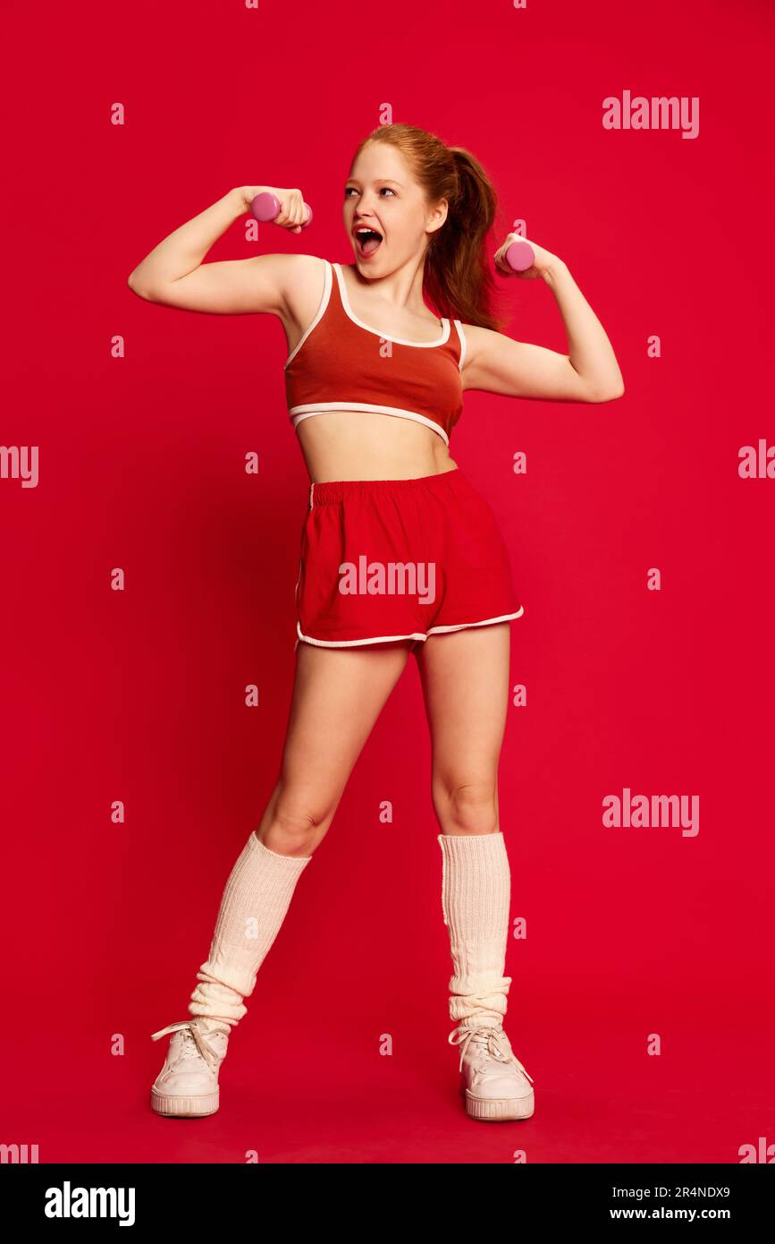 Charming red haired young girl wearing sportswear training with ...