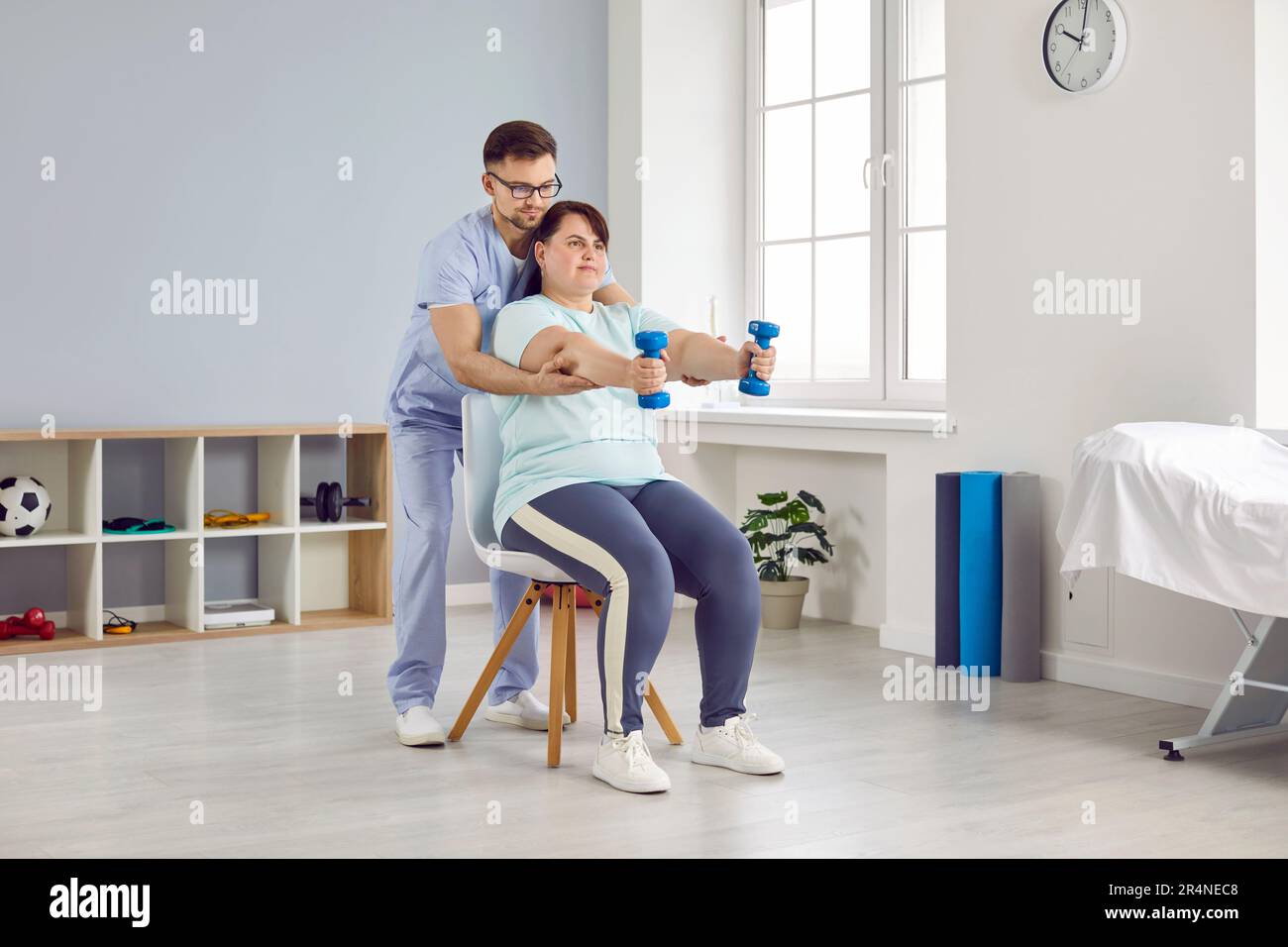 Doctor helping a young overweight woman to do physiotherapy exercises ...
