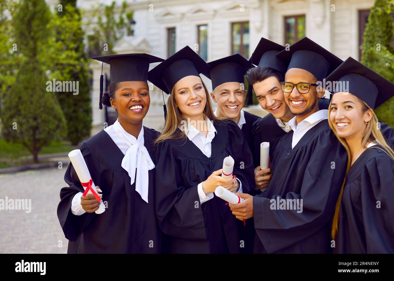Happy graduate students posing for photo in front of university ...