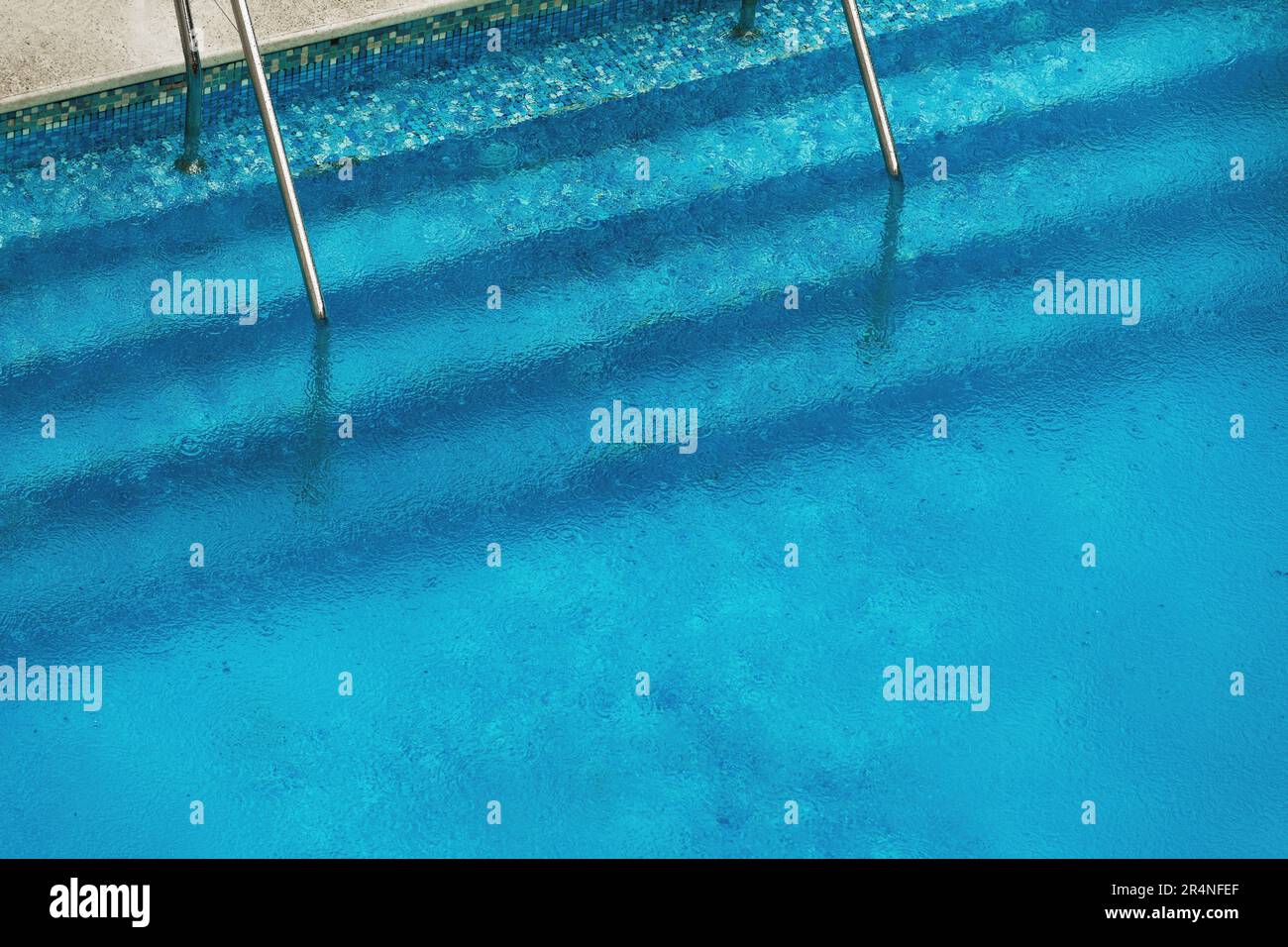 Rain drops forming circular pattern at outdoor swimming pool water ...