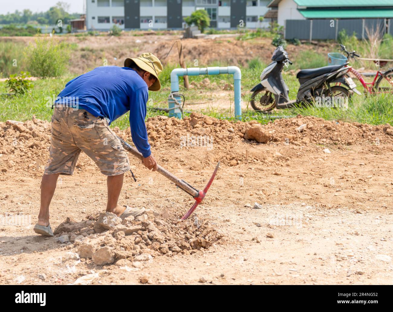 Worker digging ground with pickaxe for adjust floor before pour ...