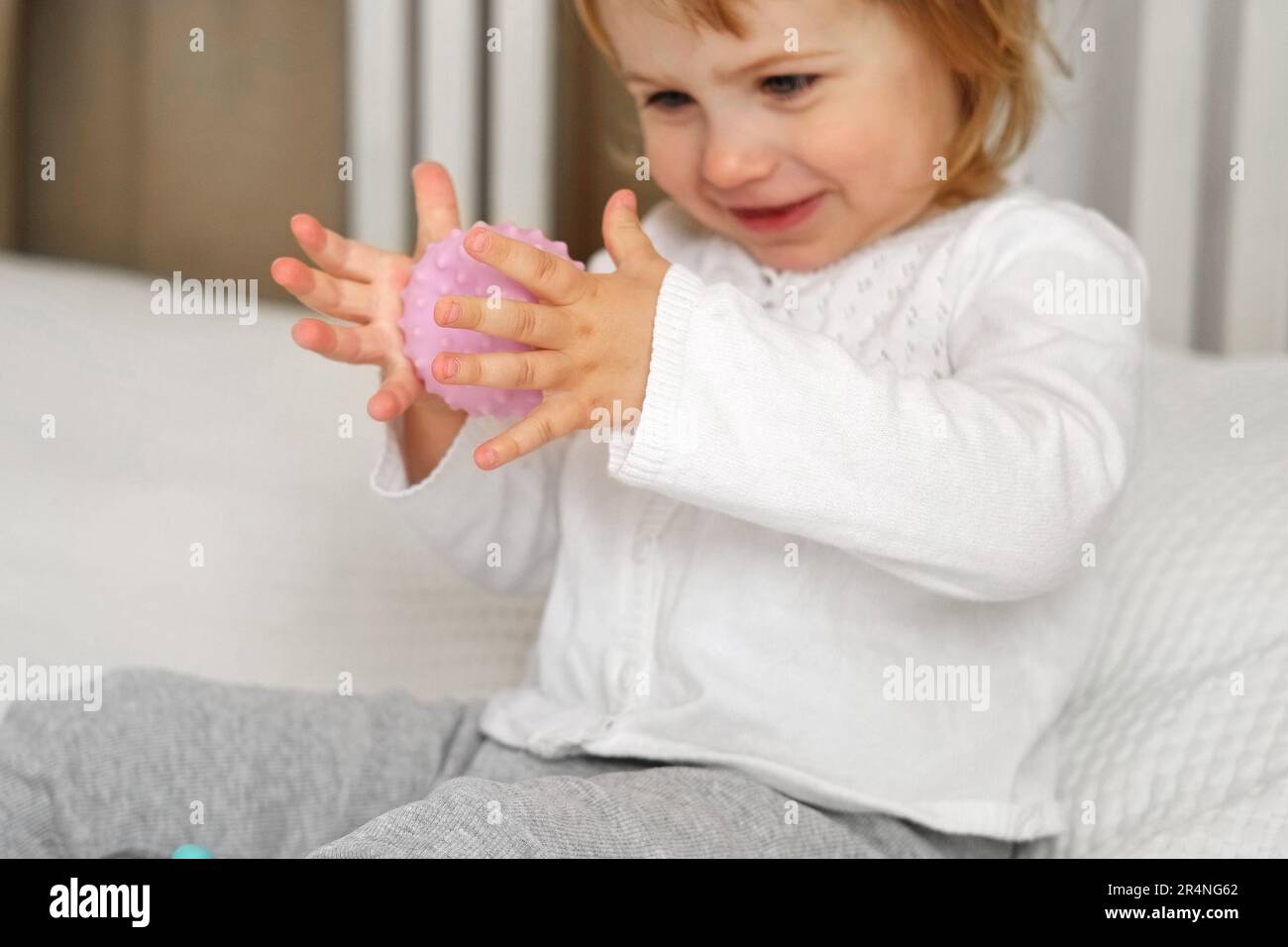 Cute baby girl playing tactile knobby balls. Young child hand plays ...