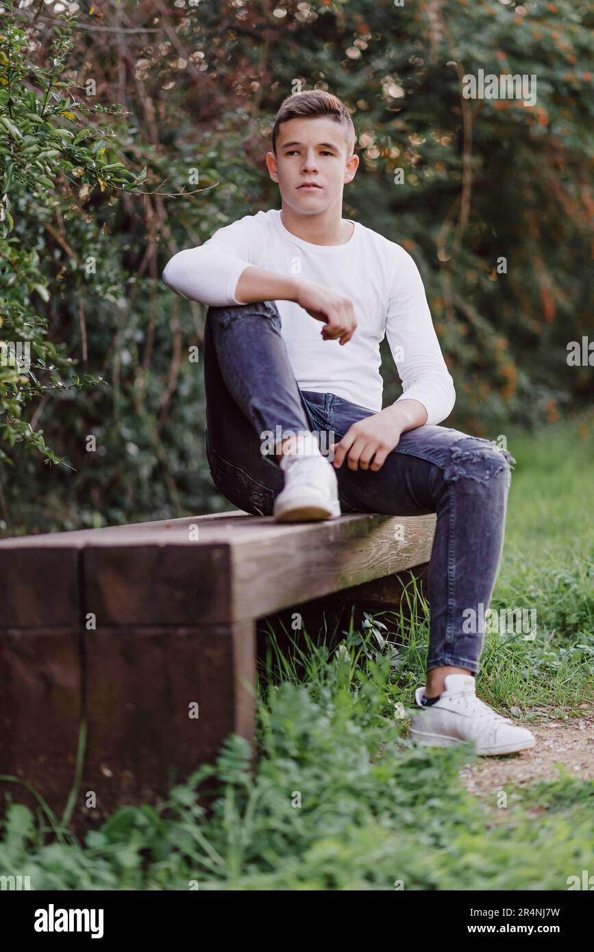 Teenager sitting on a park bench, looking camera Stock Photo - Alamy