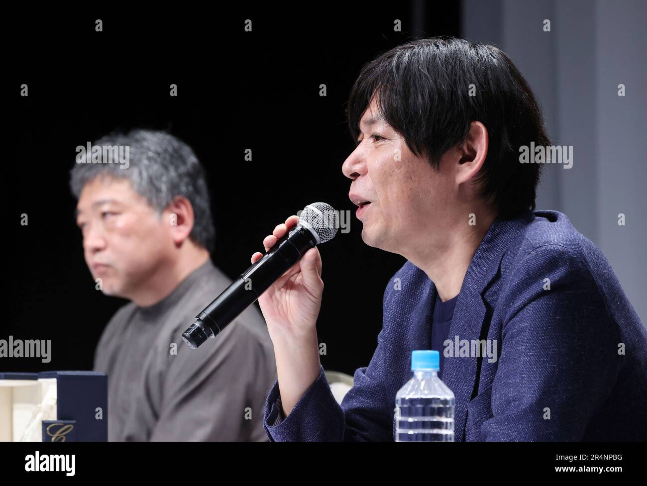 Japanese screenwriter Yuji Sakamoto (R) speaks at a press conference ...