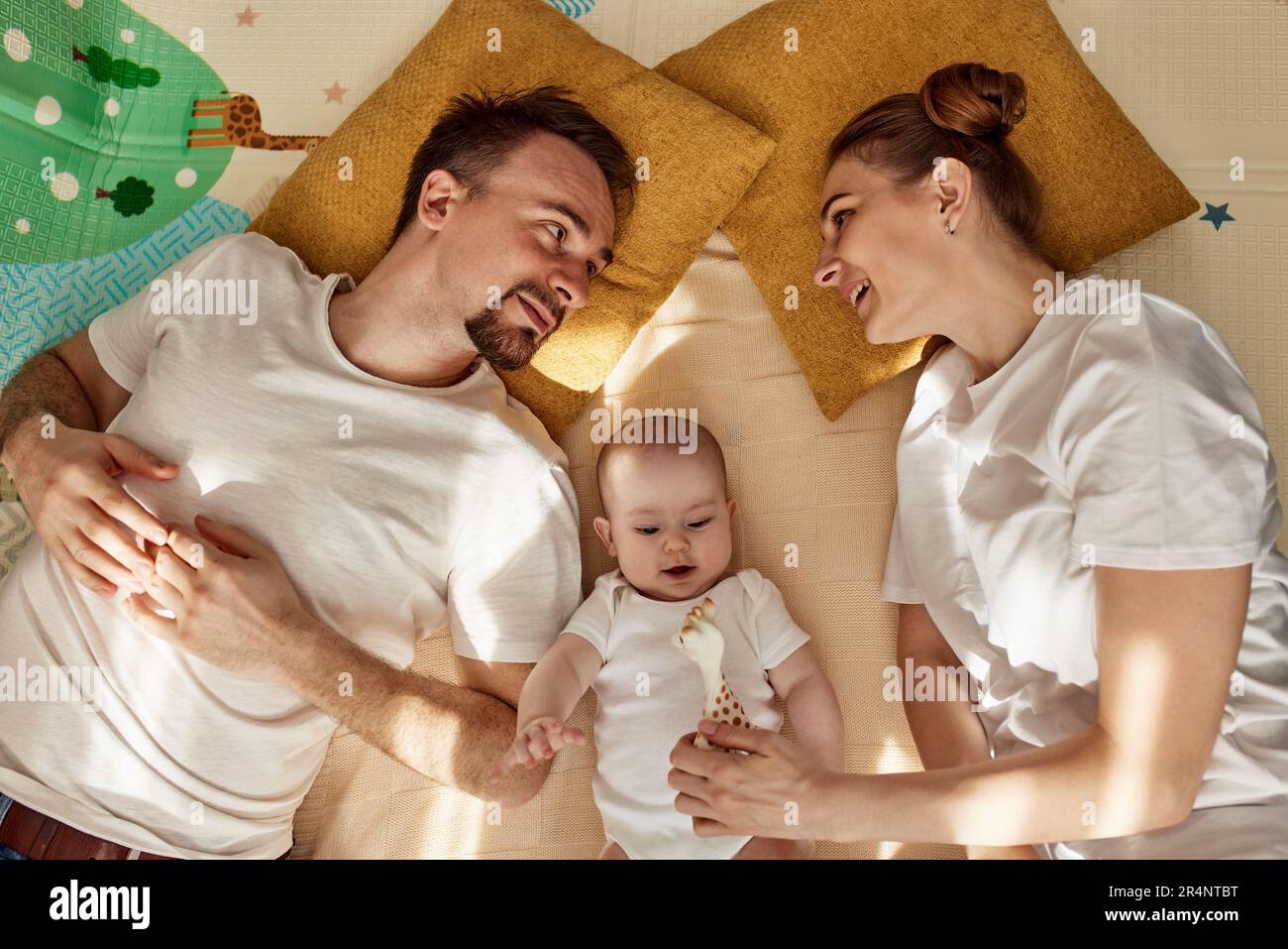 A cute joyful baby and his parents lie on the floor in a bright cozy ...