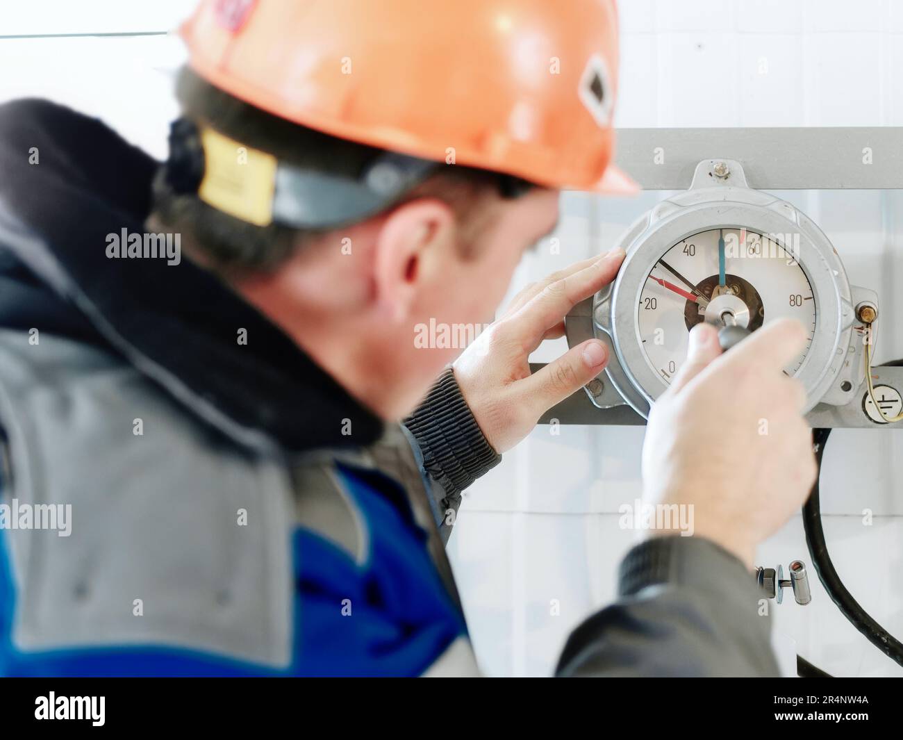 Instrumentation fitter checks and adjusts operation of pressure gauge ...