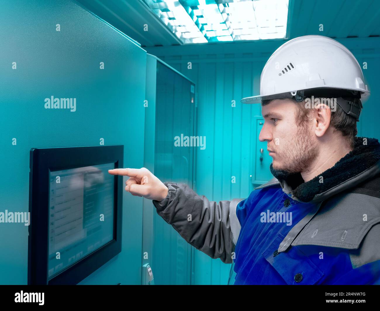 Engineer in hard hat and winter pea coat presses his finger on touch ...