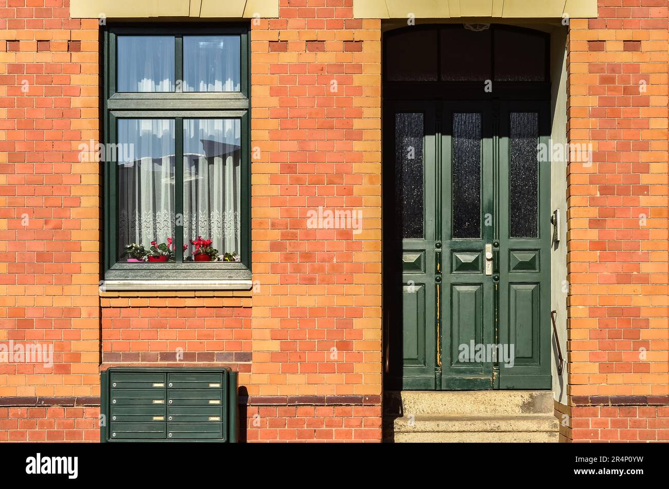 View of brick building with green wooden door, window and mailboxes ...