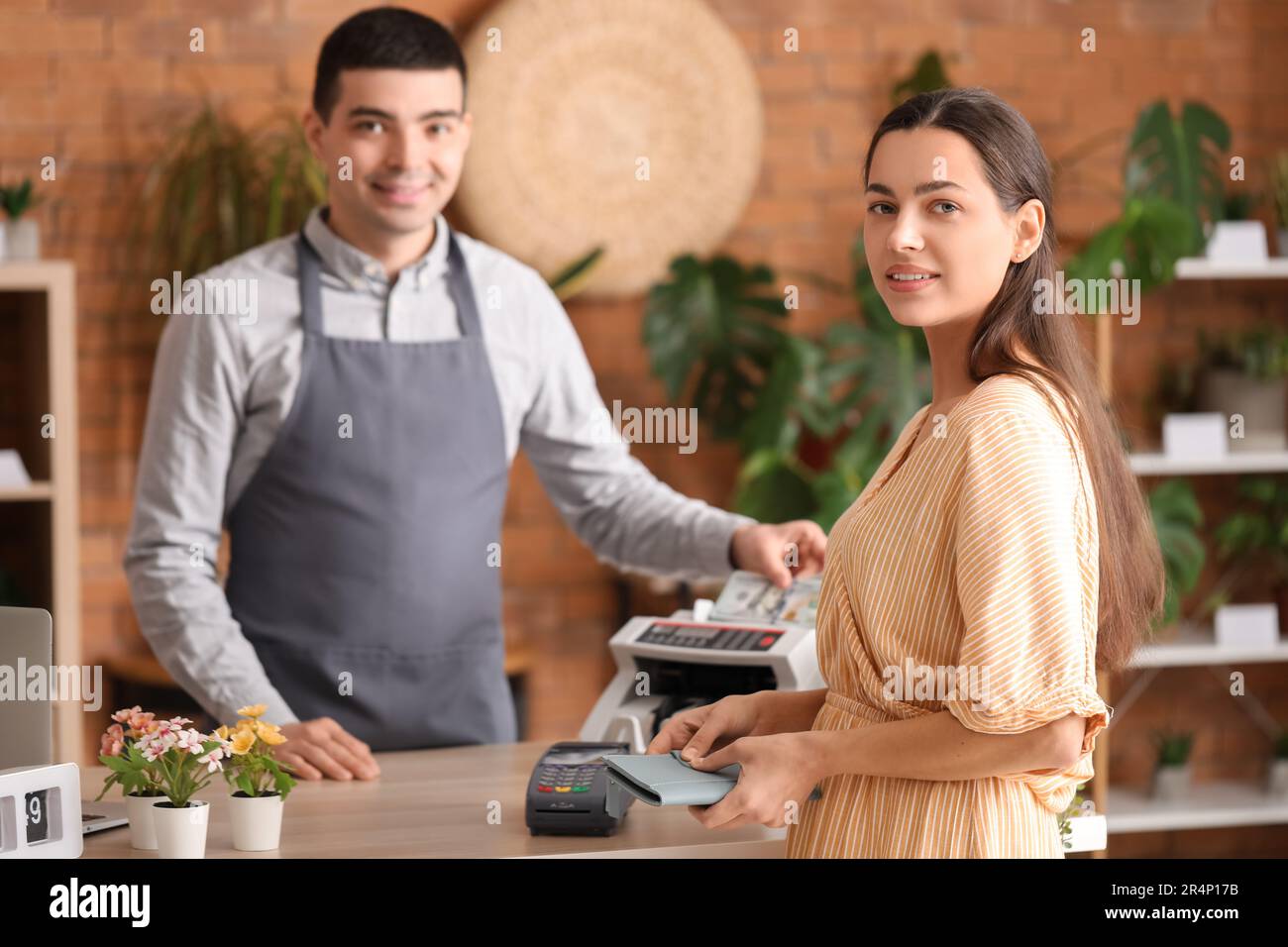 Male cashier using cash counting machine in flower shop Stock Photo - Alamy