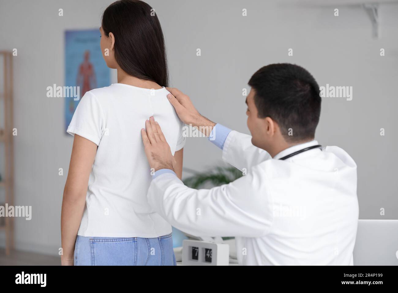 Male doctor checking posture of young woman in clinic Stock Photo - Alamy