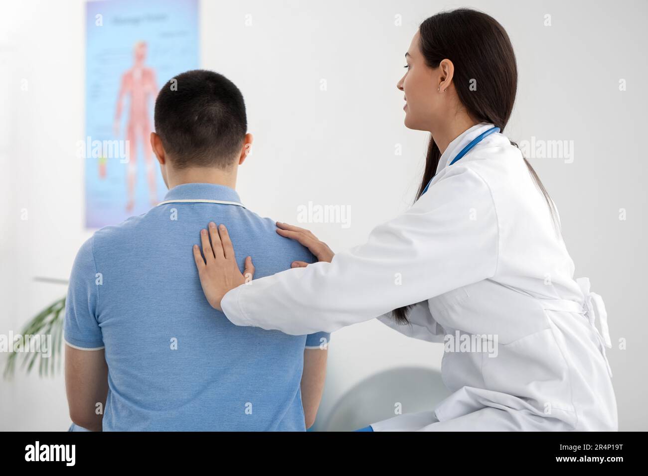 Female doctor checking posture of young man in clinic Stock Photo - Alamy