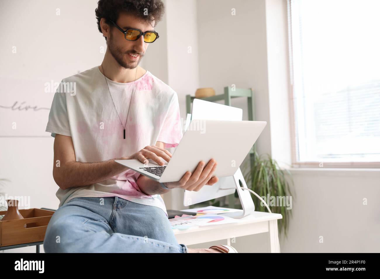 Male graphic designer working with laptop in office Stock Photo - Alamy