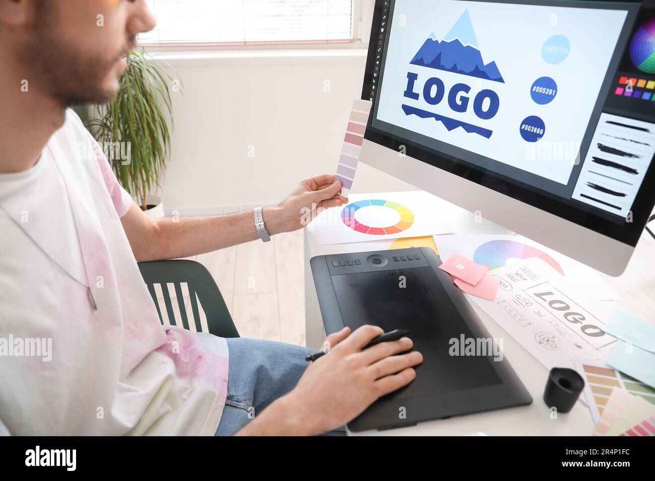 Male graphic designer working with color palette and tablet at table in ...