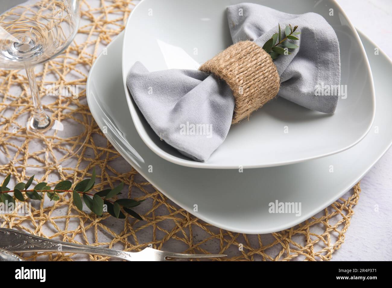 Wicker mat with plates, cutlery and glass on grunge white background ...