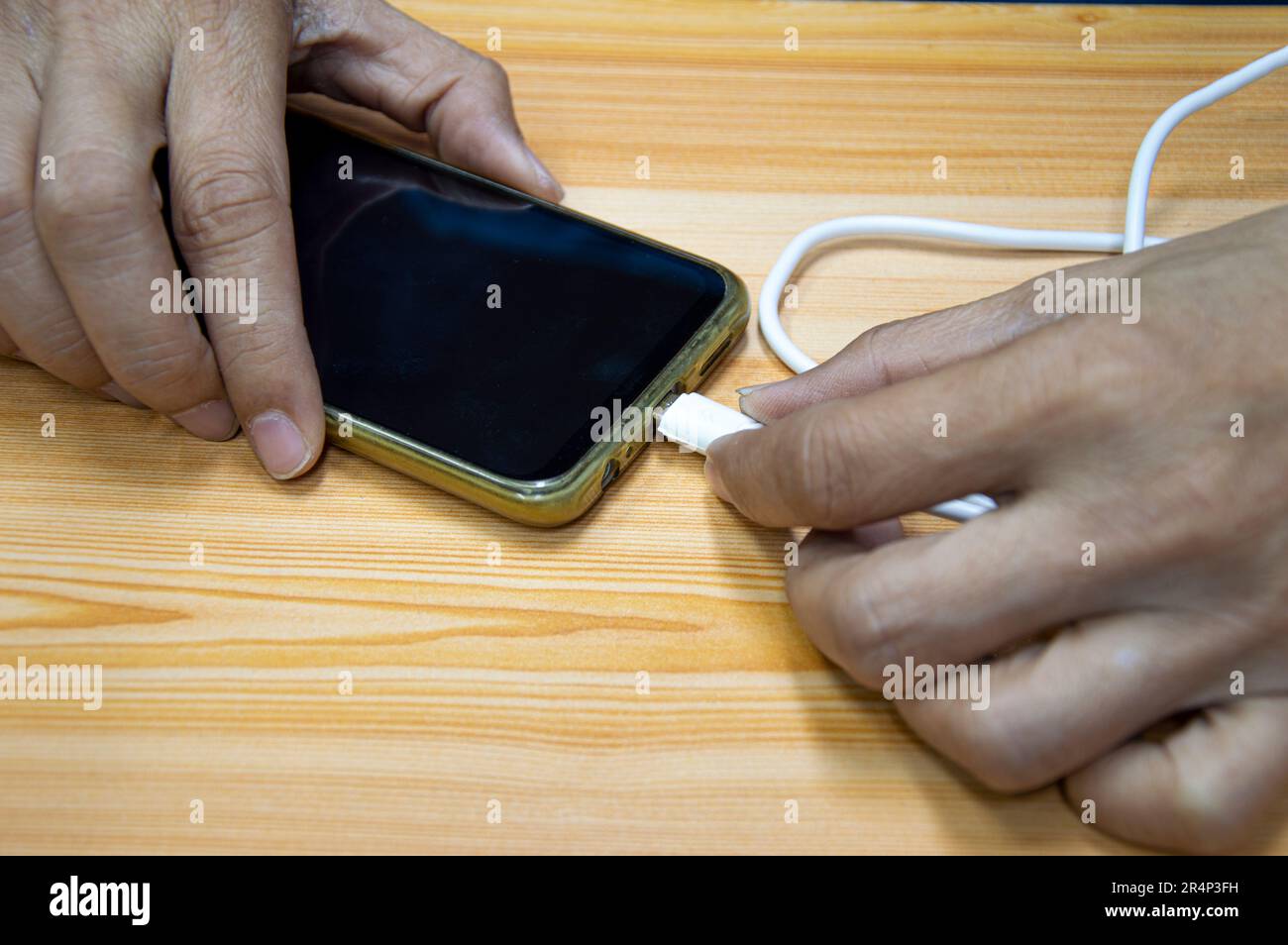 Top view. Male hand plugging in the battery charger of a smartphone ...