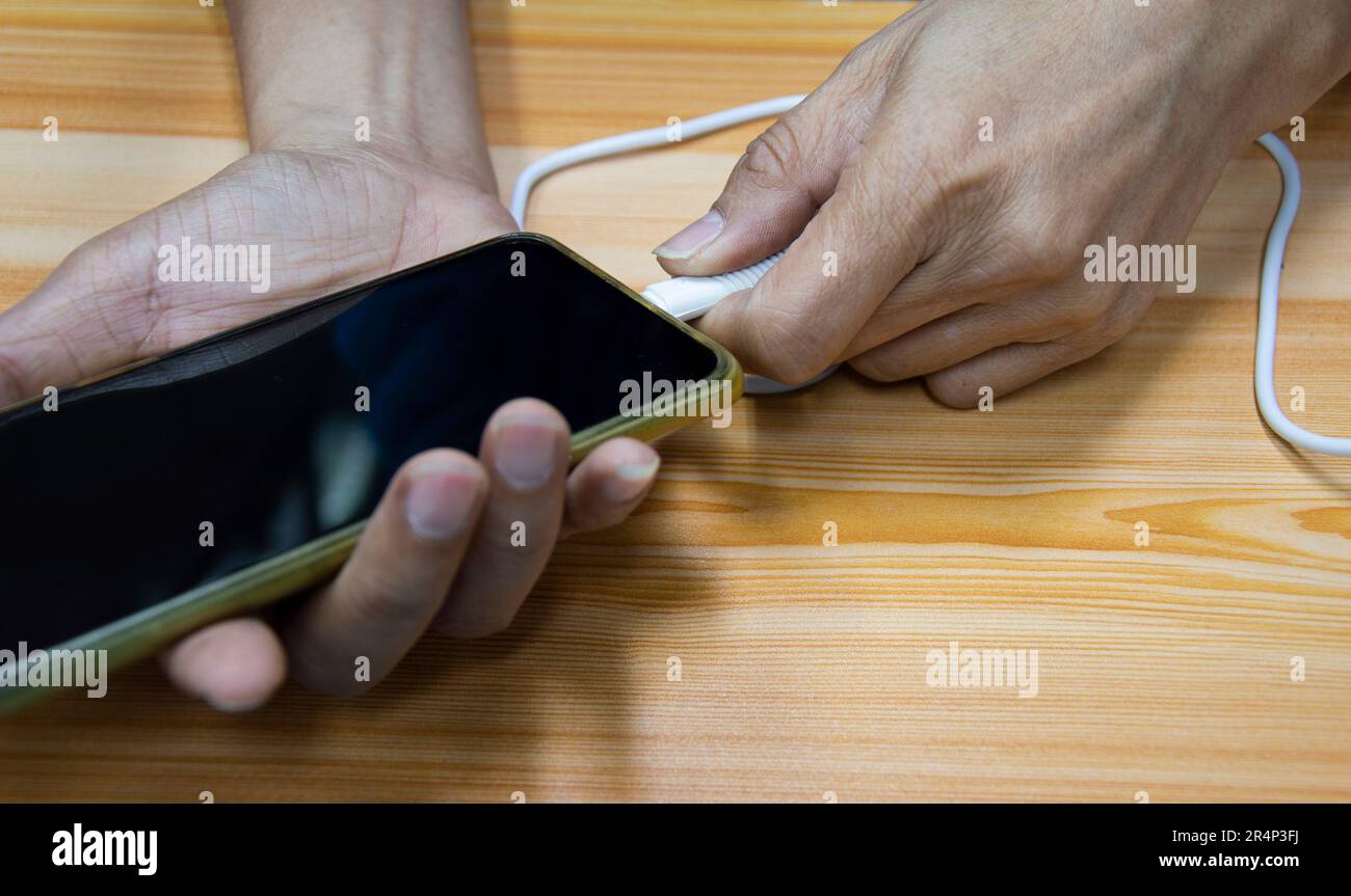 Top view. Male hand plugging in the battery charger of a smartphone ...
