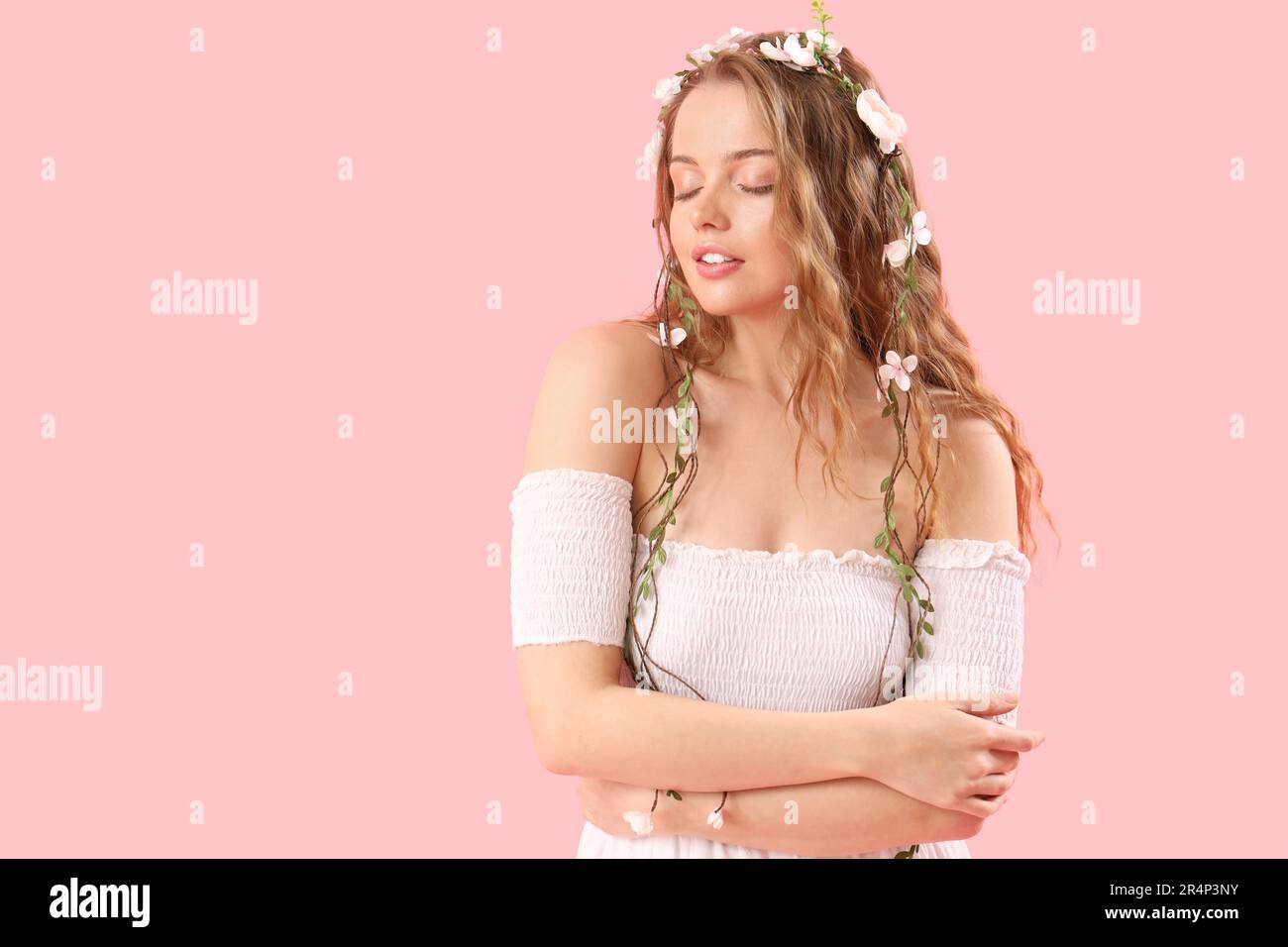 Beautiful young woman with flowers in her hair on pink background ...