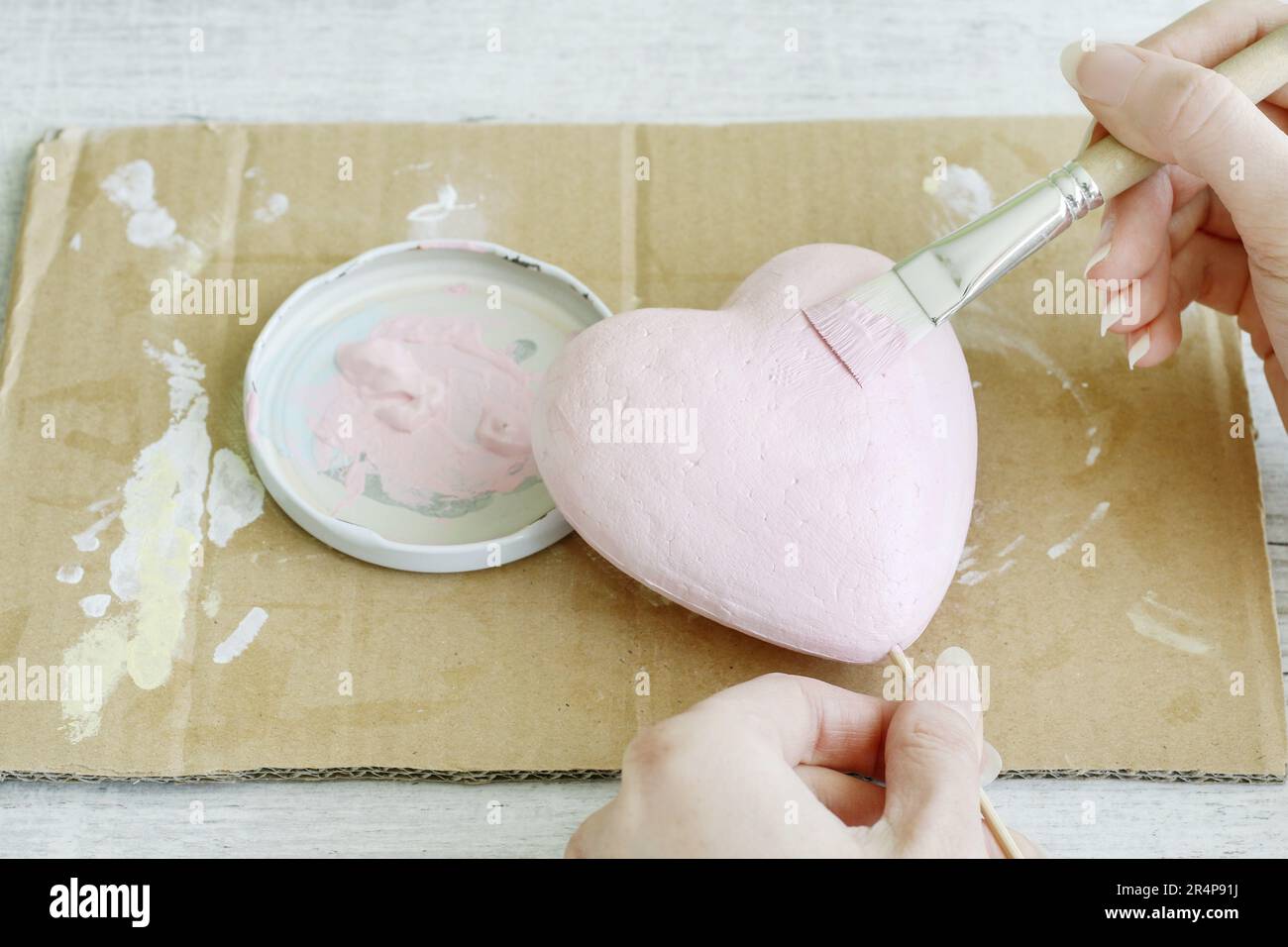 Woman paints on pink color a styrofoam heart. Hobby time Stock Photo ...