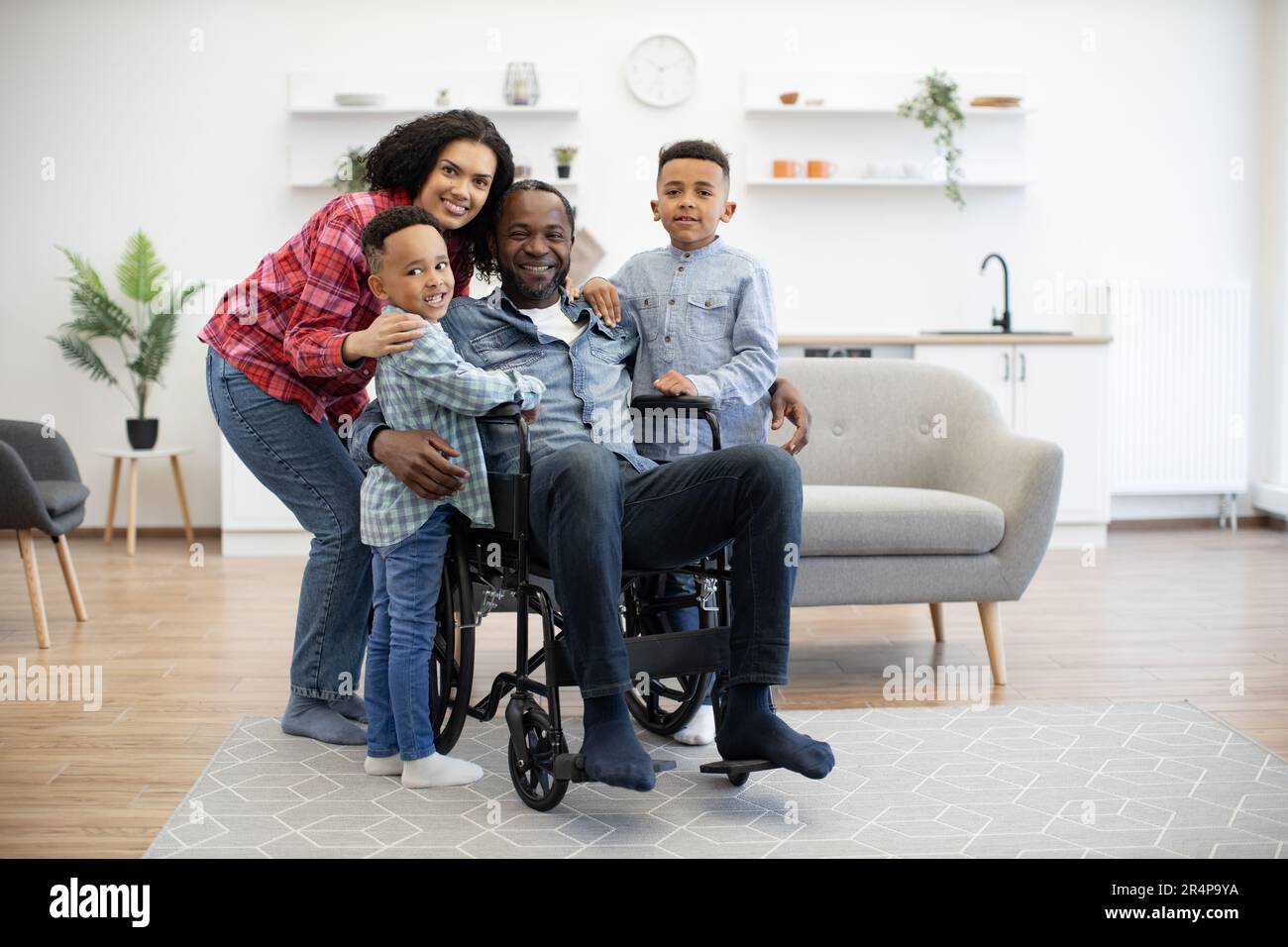 Full length portrait of happy multicultural family of four hugging each ...