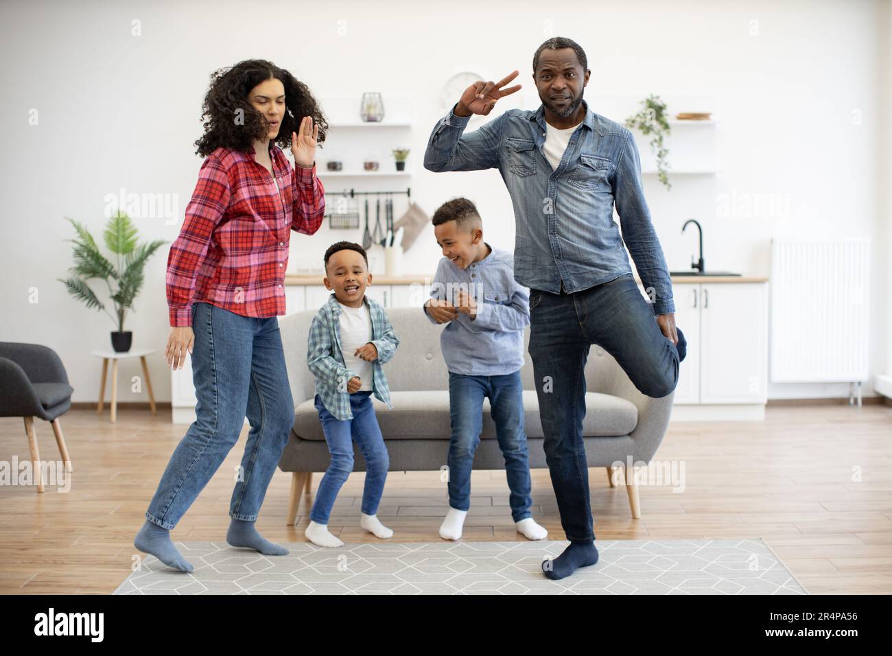 Dynamic multiethnic family of four having dancing party in bright ...