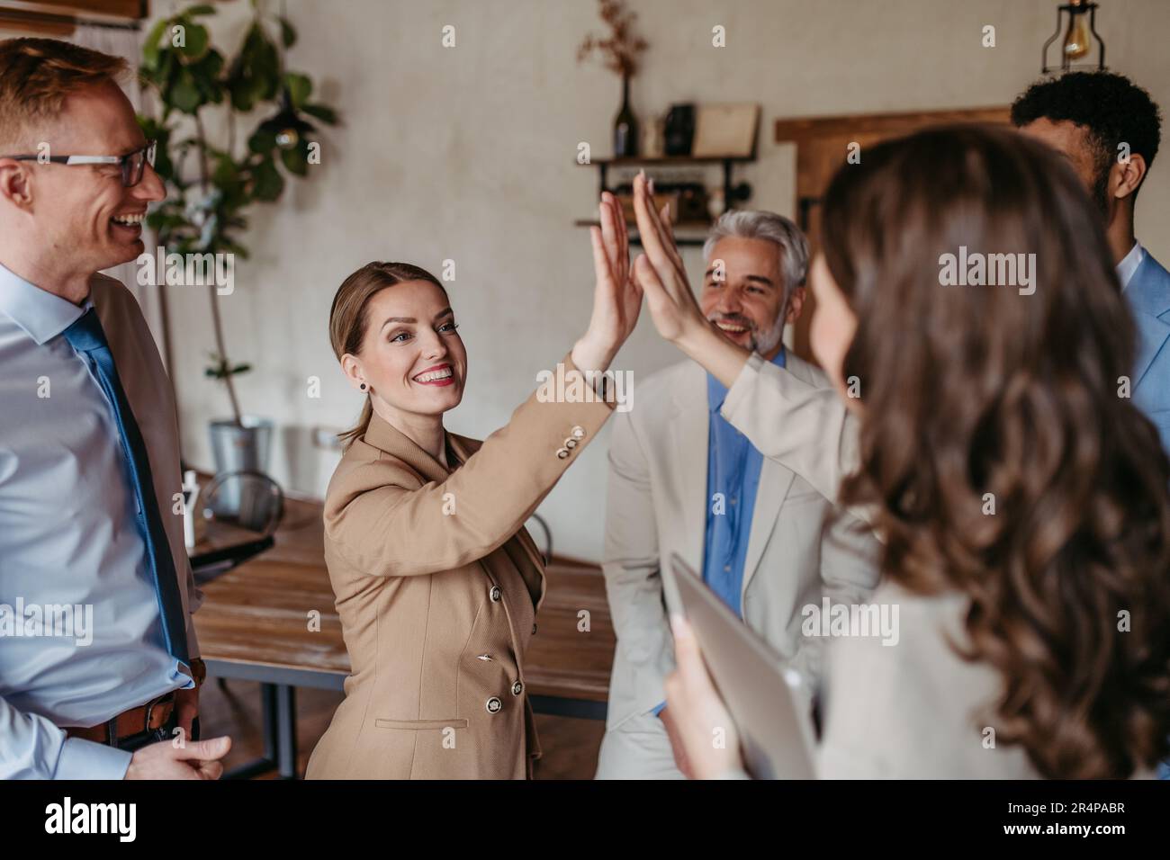 Happy business team giving a high fives gesture as they laugh and ...