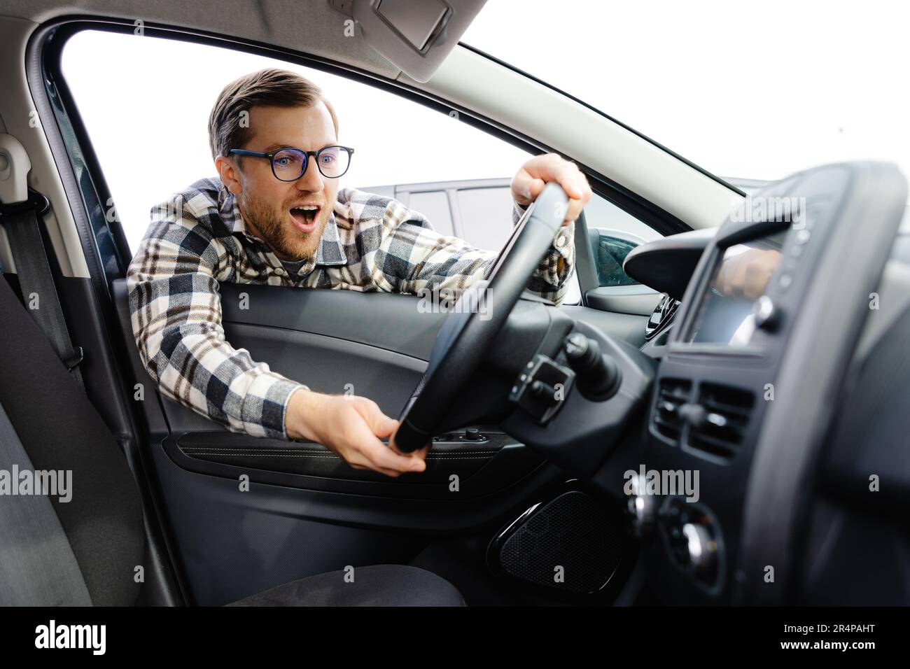 Young man looking through window inside new car, checking it before ...