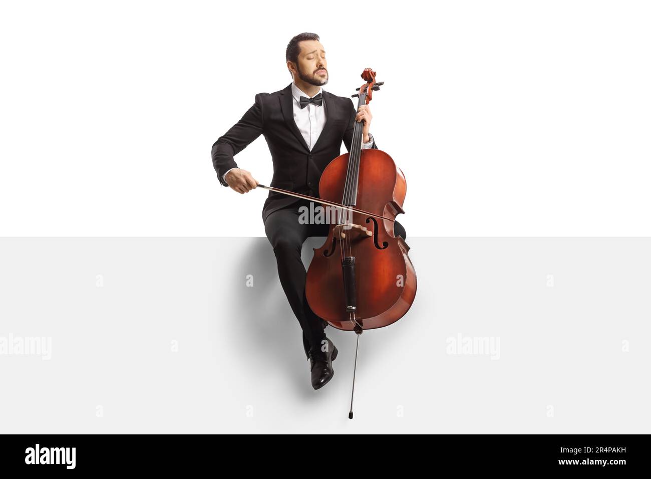 Male musician in a black suit and bow-tie sitting on a blank panel with ...