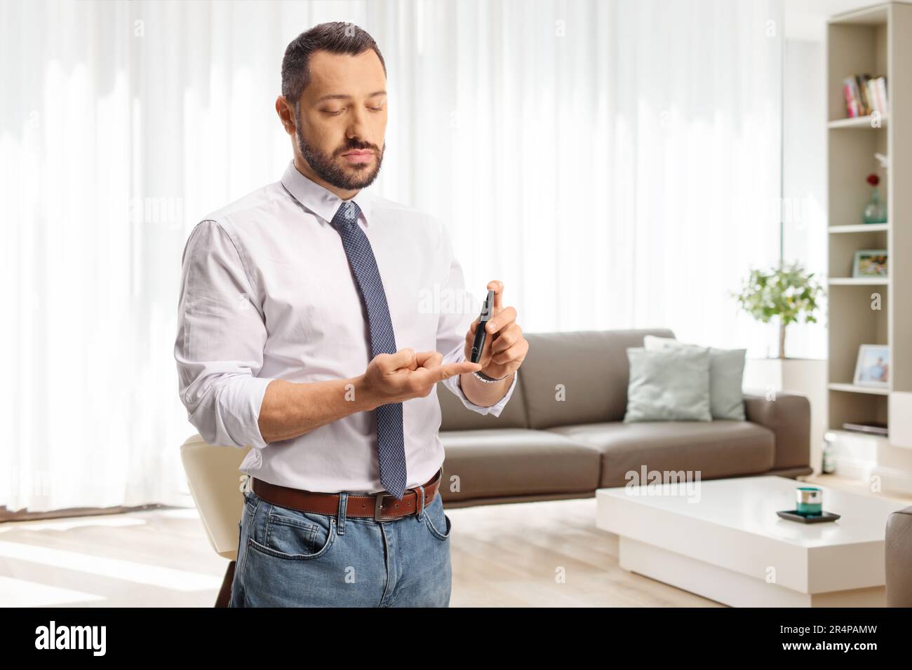 Young man pricking finger with a medical device at home Stock Photo - Alamy