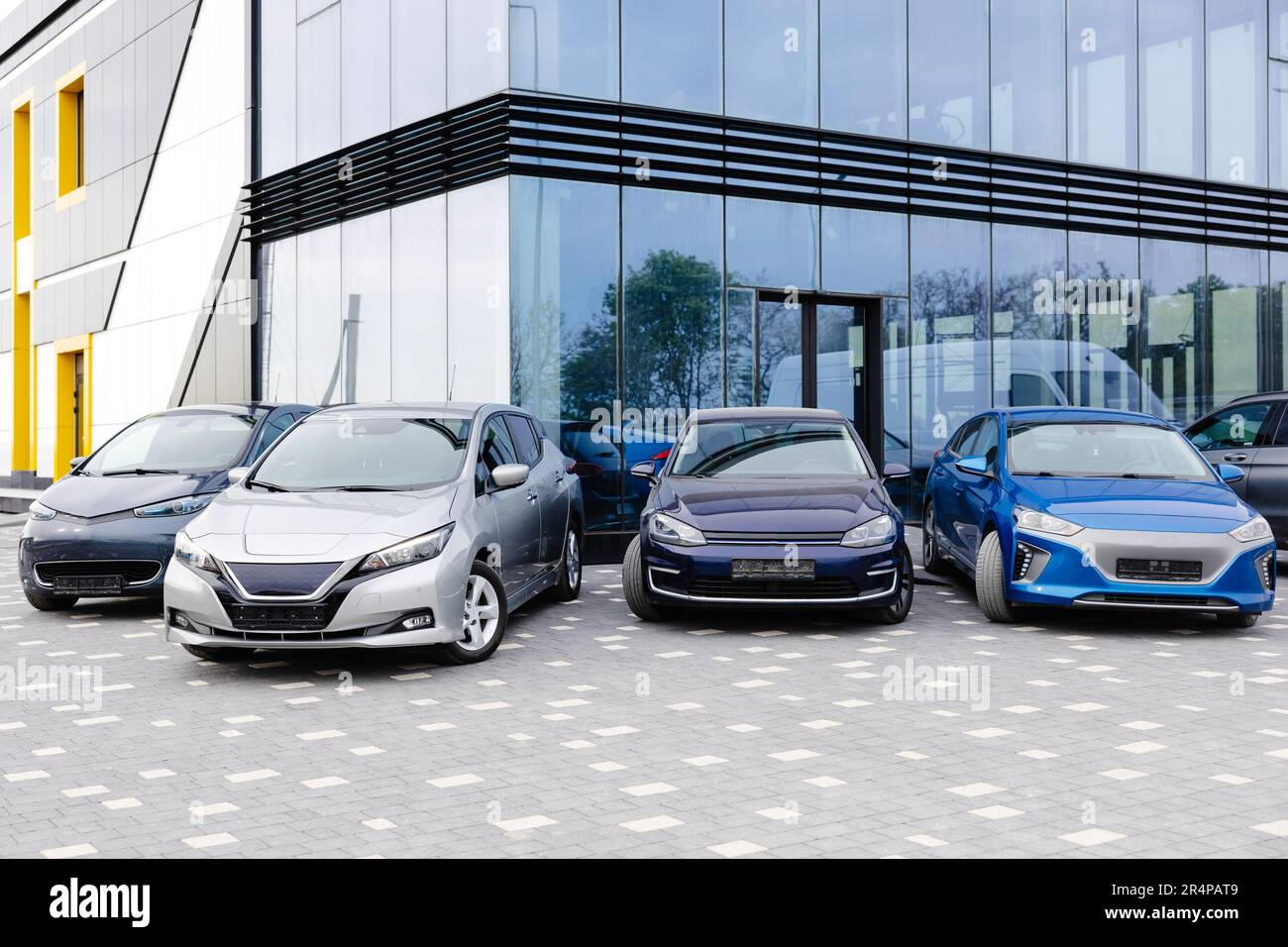 Side view of red electric car hood standing beside new cars for sell ...
