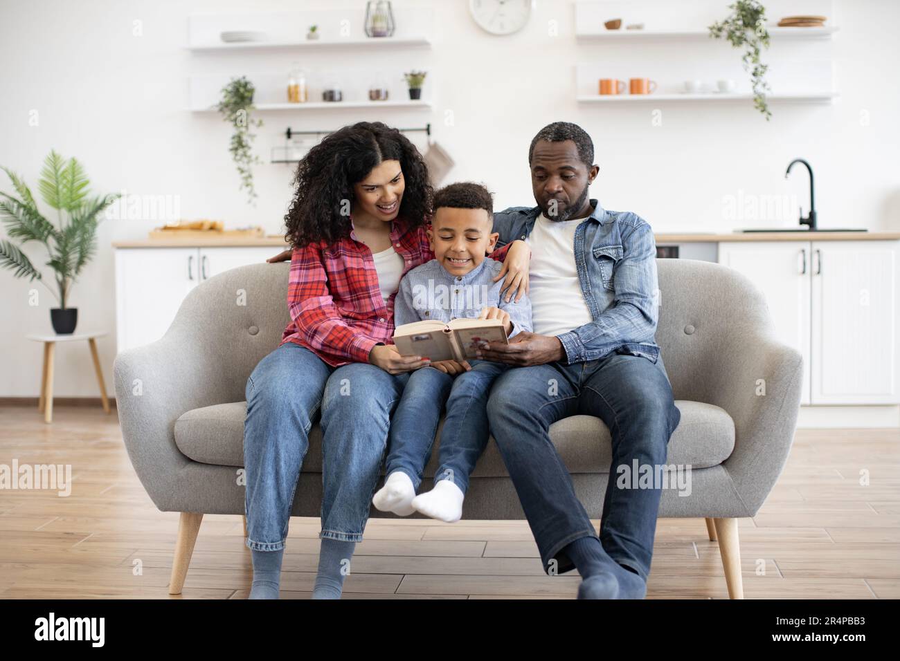 Caring multicultural parents sitting near preschool boy with paper book ...