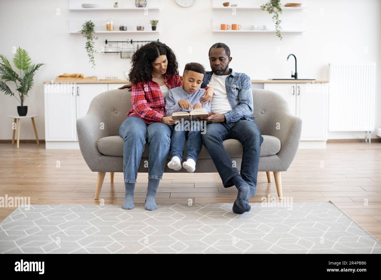 Caring multicultural parents sitting near preschool boy with paper book ...