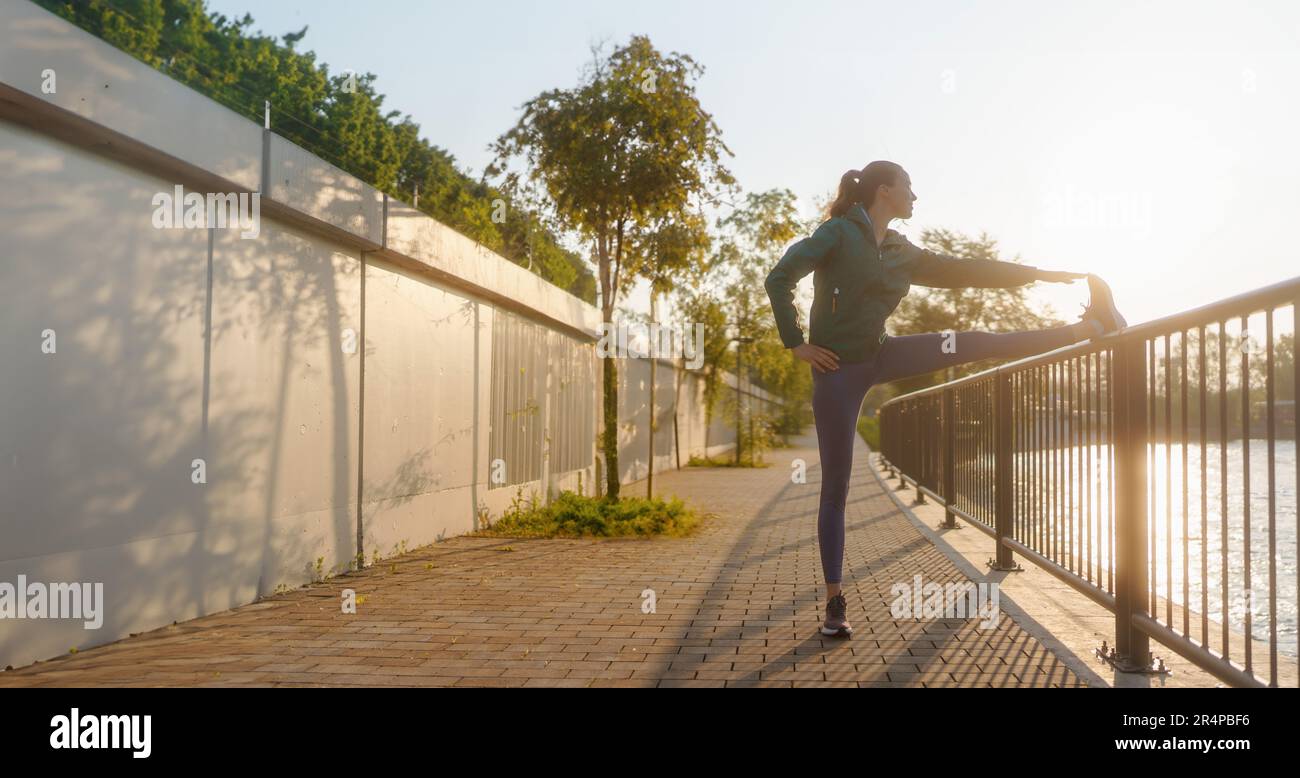Athletic young woman in sportswear doing stretching exercises before ...