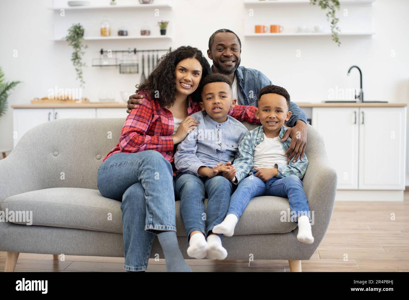 Portrait of multiracial four-person family posing together on soft ...