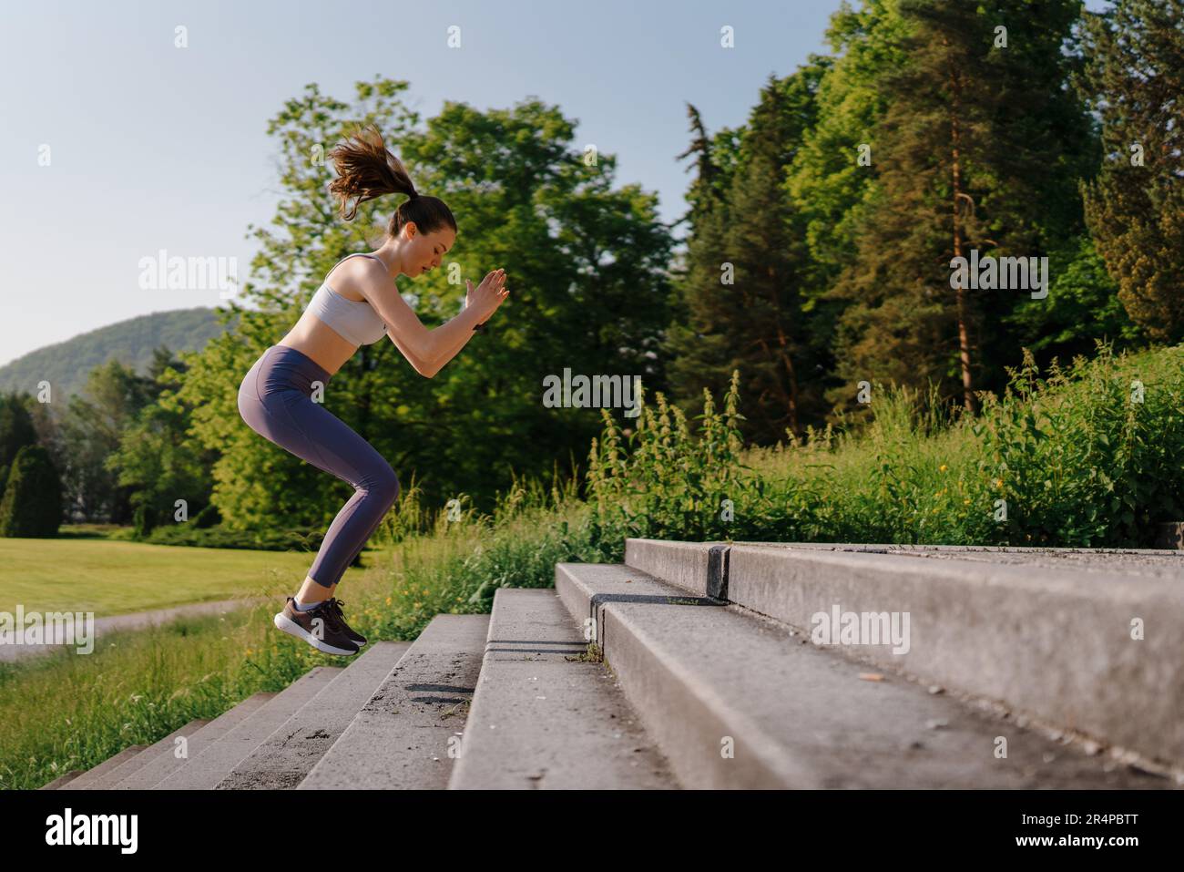 Sporty woman doing jumping squats exercise on stairs in city park Stock ...